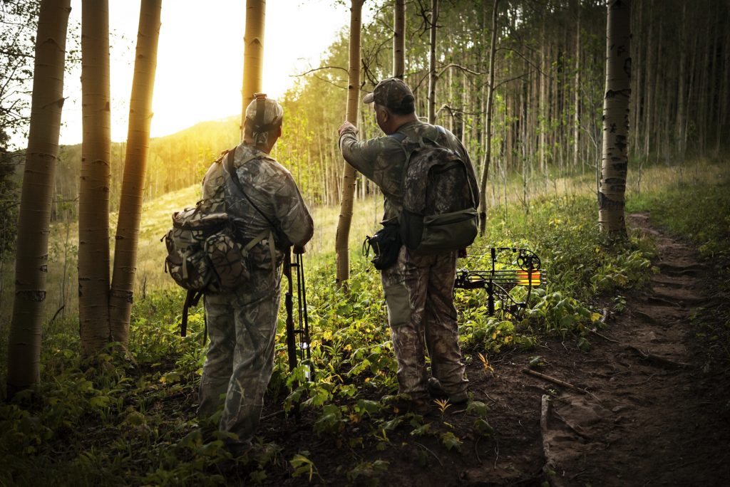 Rear view of hunters discussing in forest | Blain's Farm & Fleet Blog